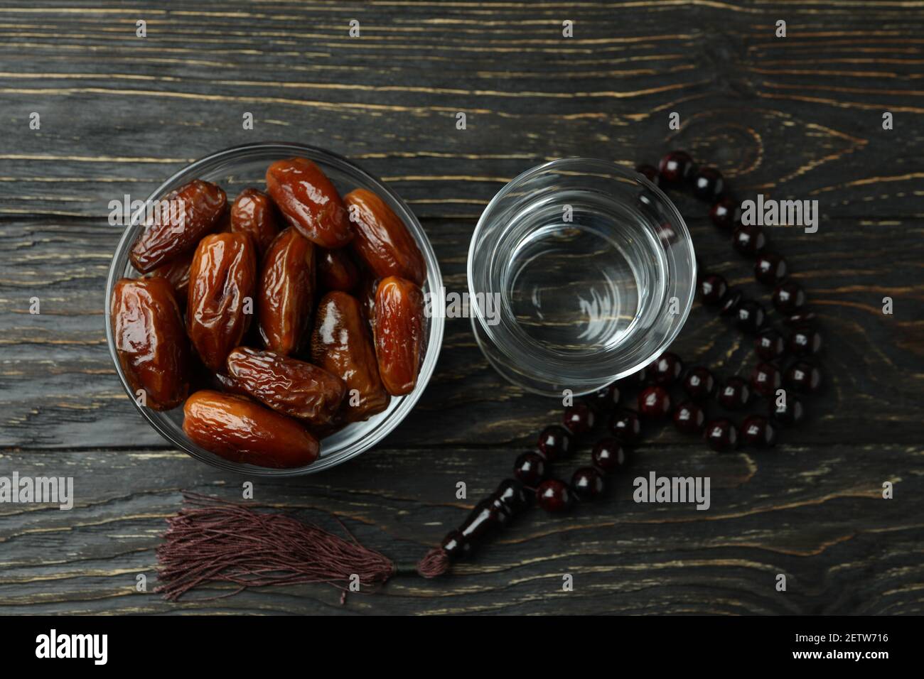 Glass of water, bowl of dates and rosary on wooden background Stock ...