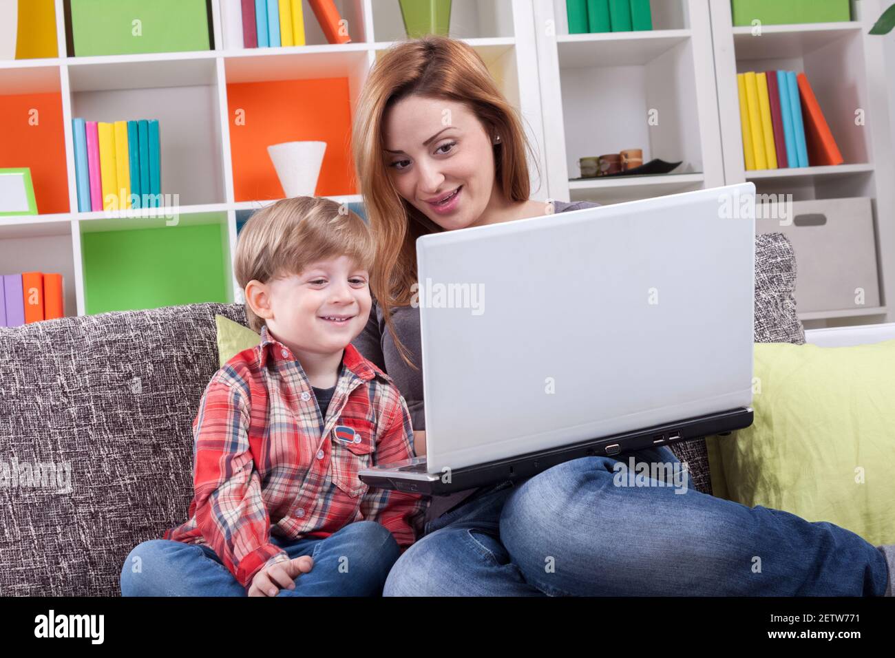 Happy mother and son using computer on the couch Stock Photo - Alamy