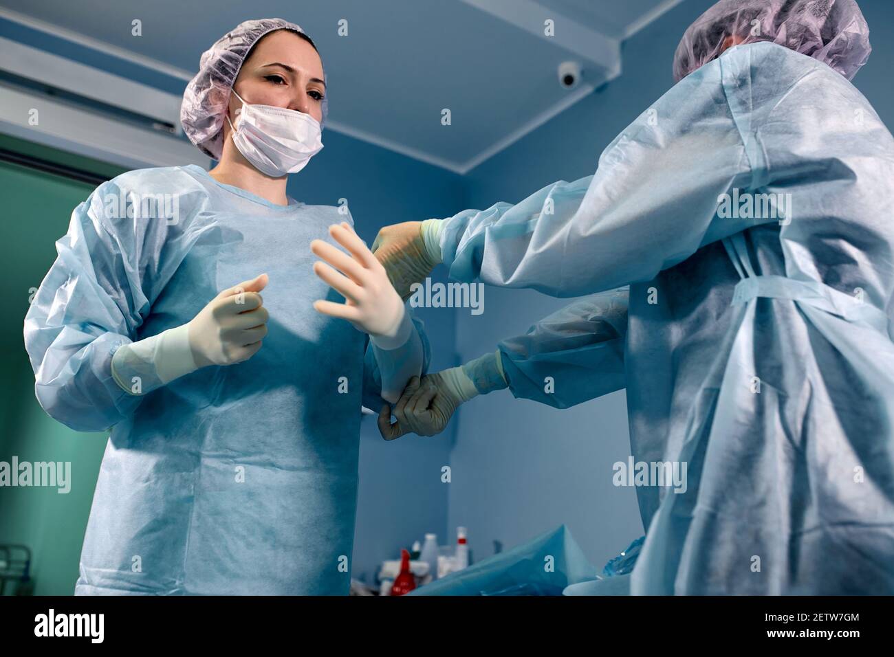 Profile view of a medical assistant helping a surgeon put on his gloves ...