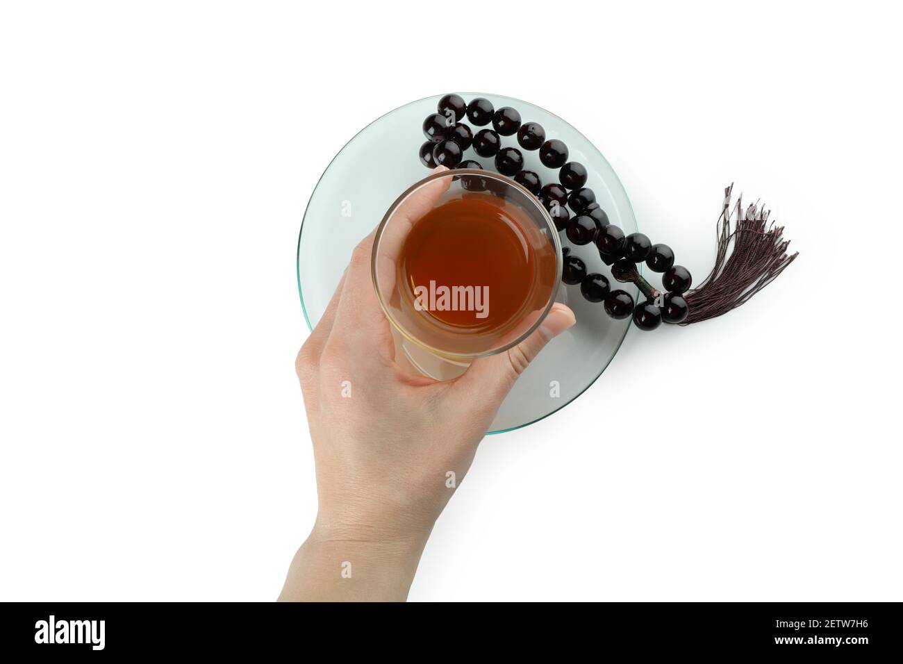Female hand hold glass of tea on saucer with rosary, isolated on white ...