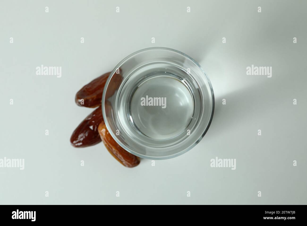 Glass of water and dates on white background Stock Photo - Alamy