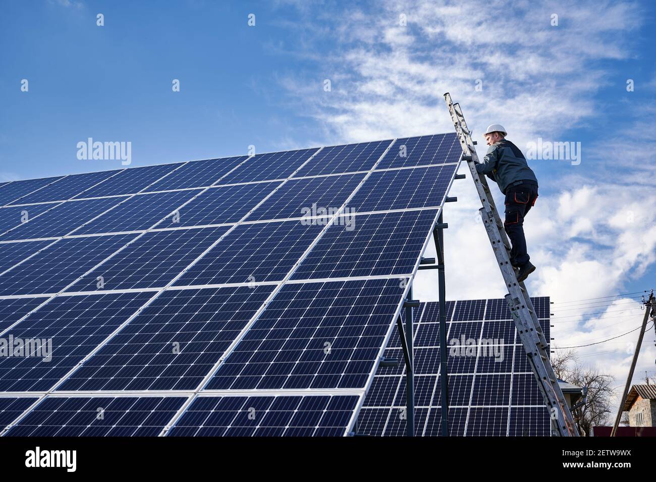 Side view of man technician in safety helmet climbing the ladder to get ...