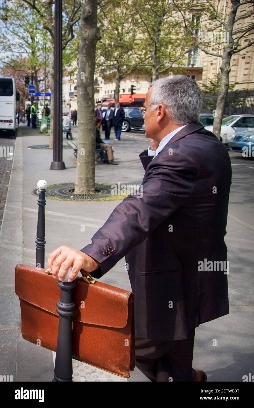 A business man in a suit stands with a briefcase in his hands Stock ...