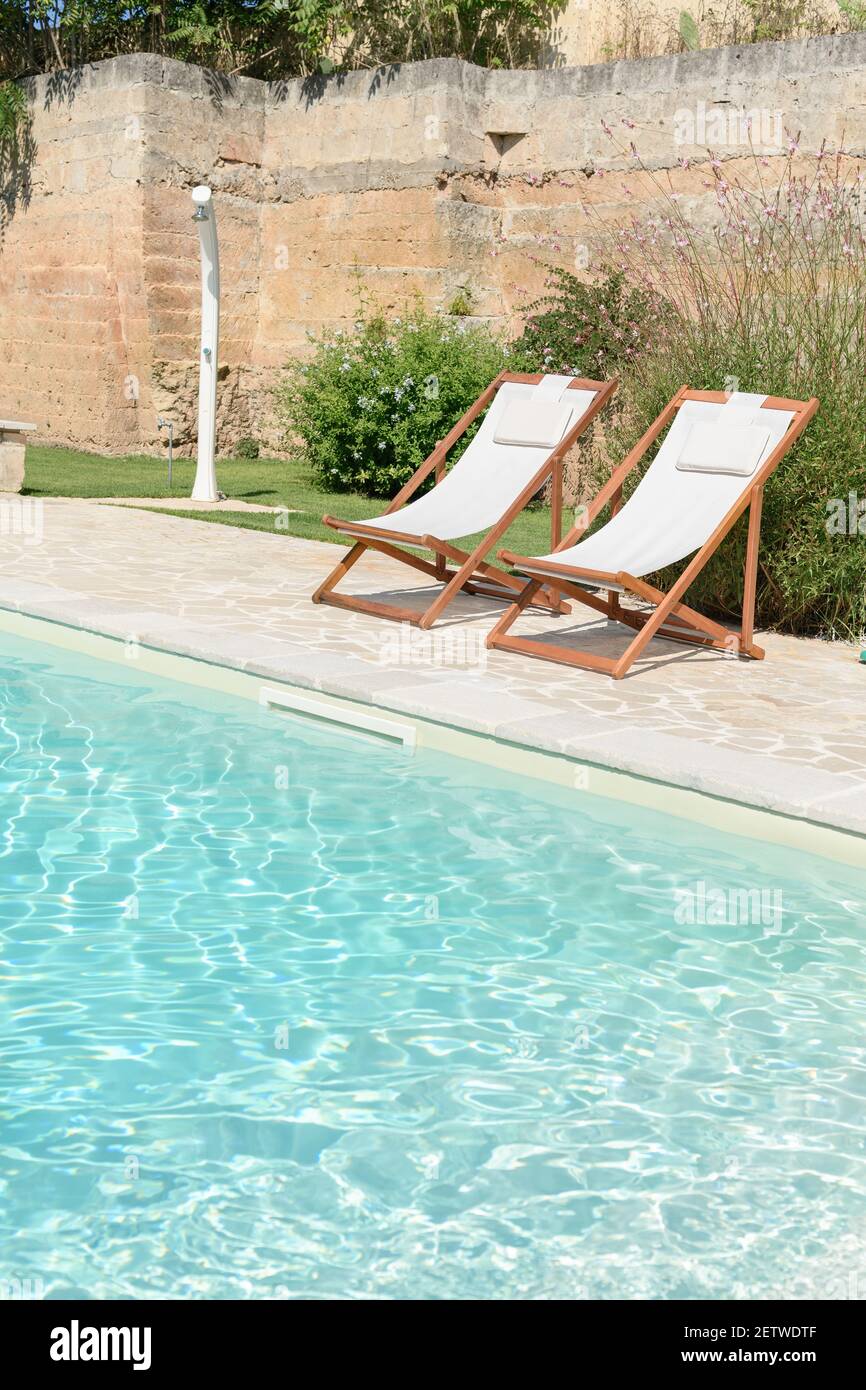 Swim pool with clear blue water and two sun bed on sunny day in a yard ...