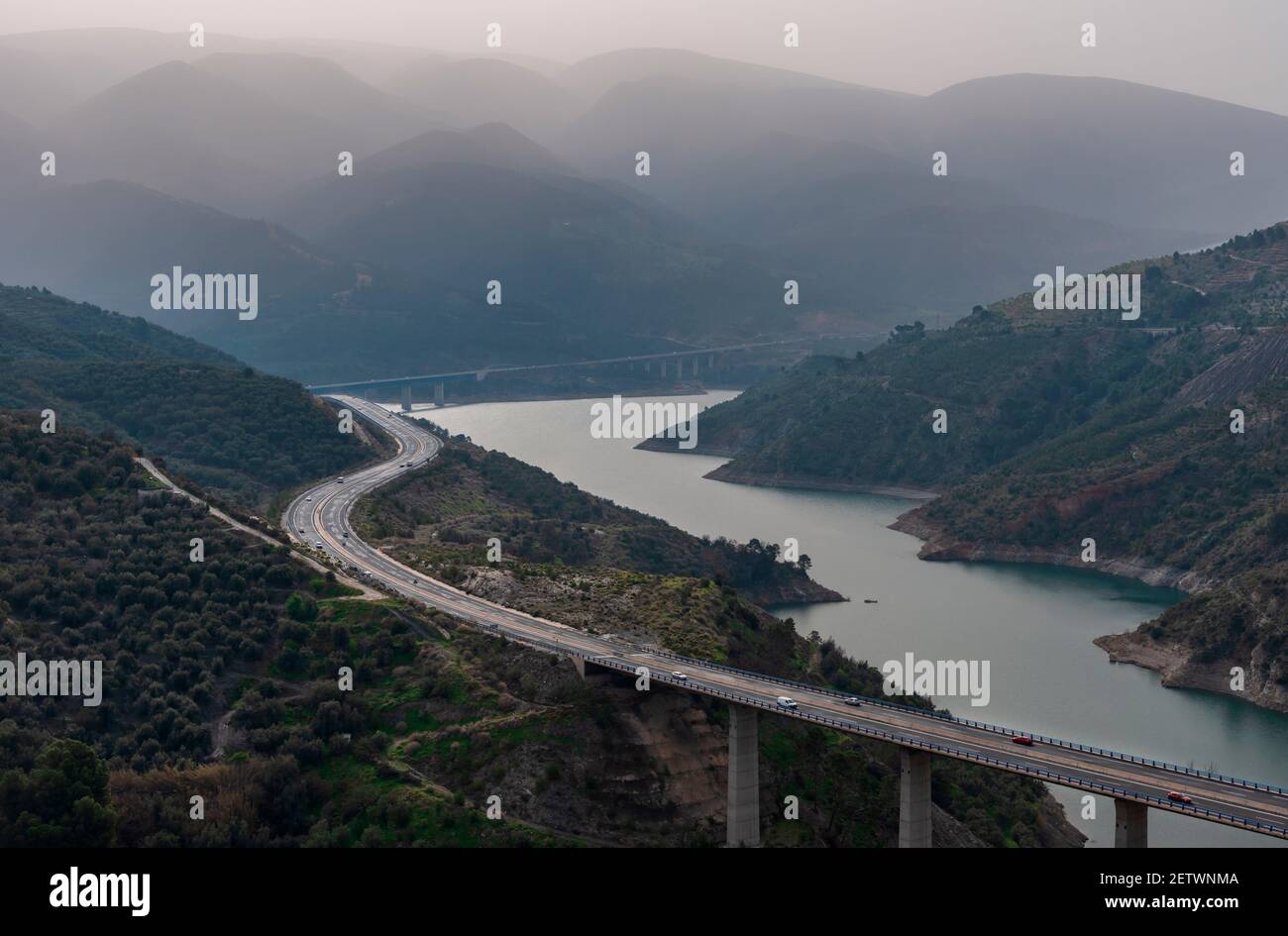 Highway between mountains and bordering a reservoir Stock Photo - Alamy