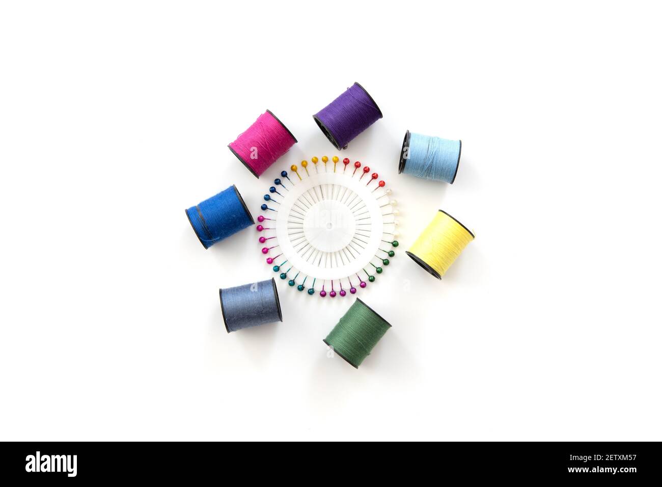 Colored needles and thread reel on patterned fabric placed on the left ...