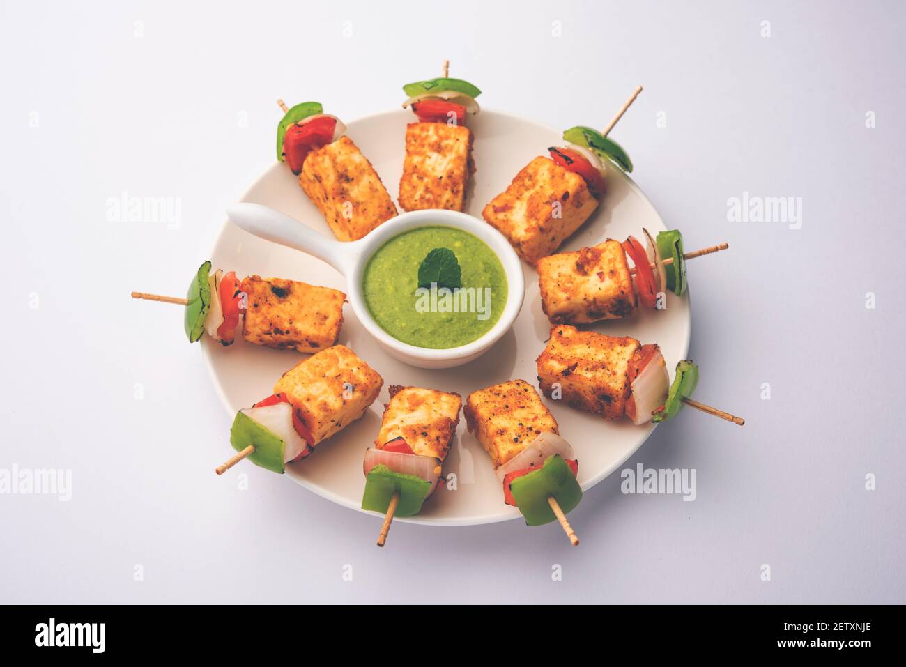 Starter snack Paneer Tikka with stick in plate with green chutney ...