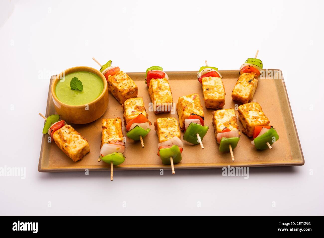Starter snack Paneer Tikka with stick in plate with green chutney ...