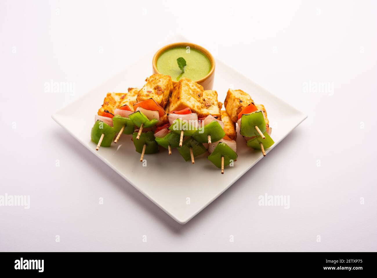Starter snack Paneer Tikka with stick in plate with green chutney ...