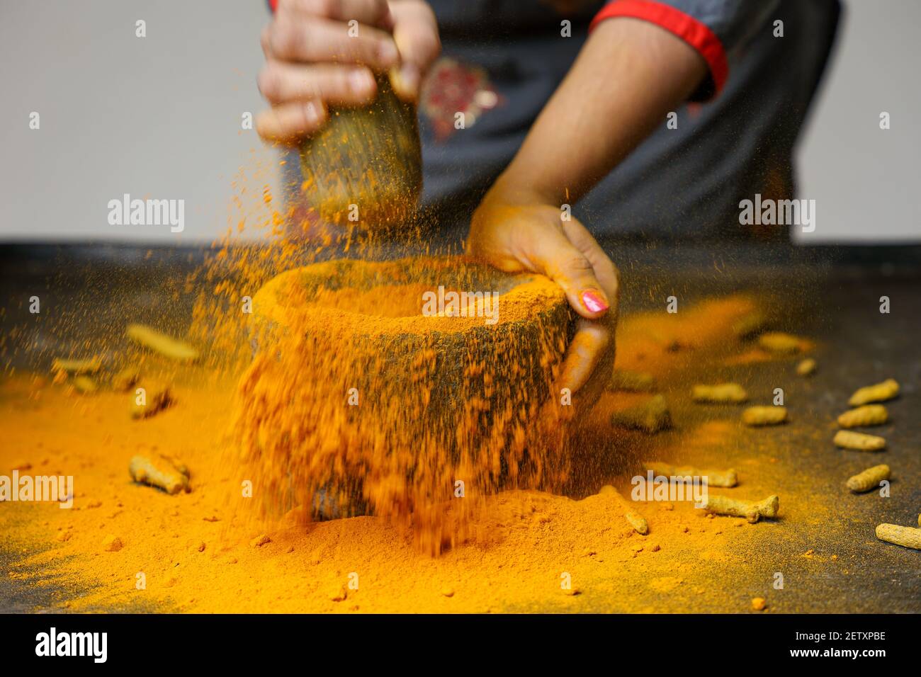 Woman hand powdering Indian spices turmeric powder splash explosion ...