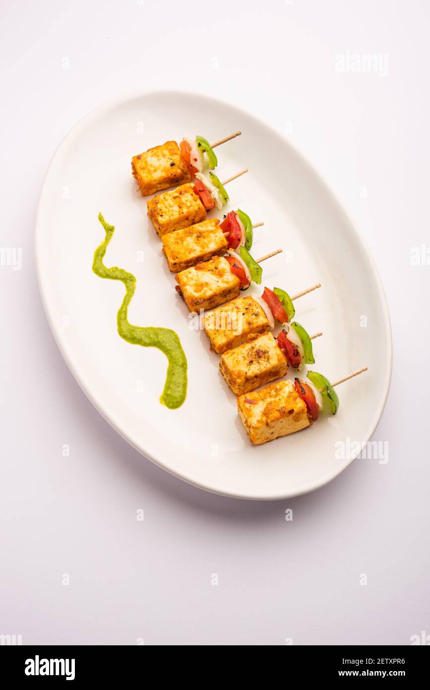 Starter snack Paneer Tikka with stick in plate with green chutney ...