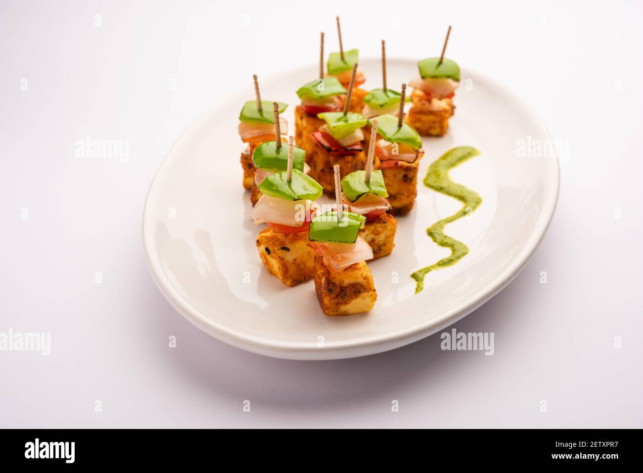 Starter snack Paneer Tikka with stick in plate with green chutney ...