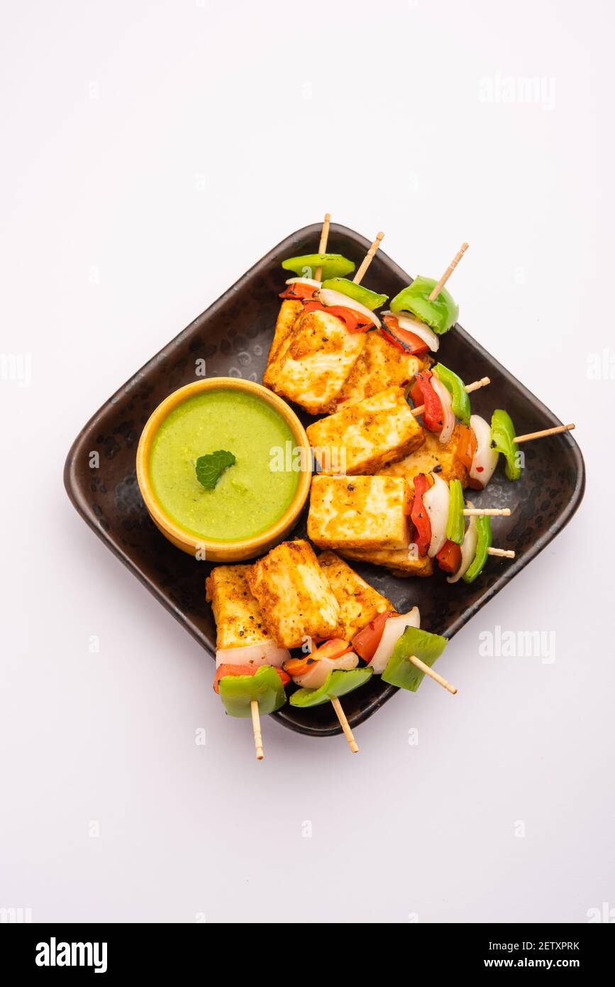 Starter snack Paneer Tikka with stick in plate with green chutney ...