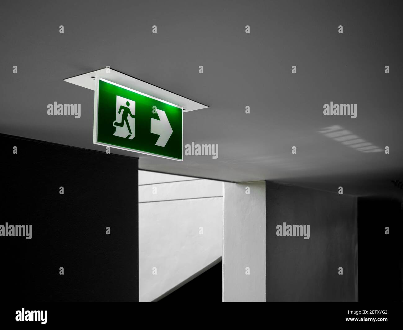 Fire exit sign. Green emergency exit sign hanging from ceiling glowing ...