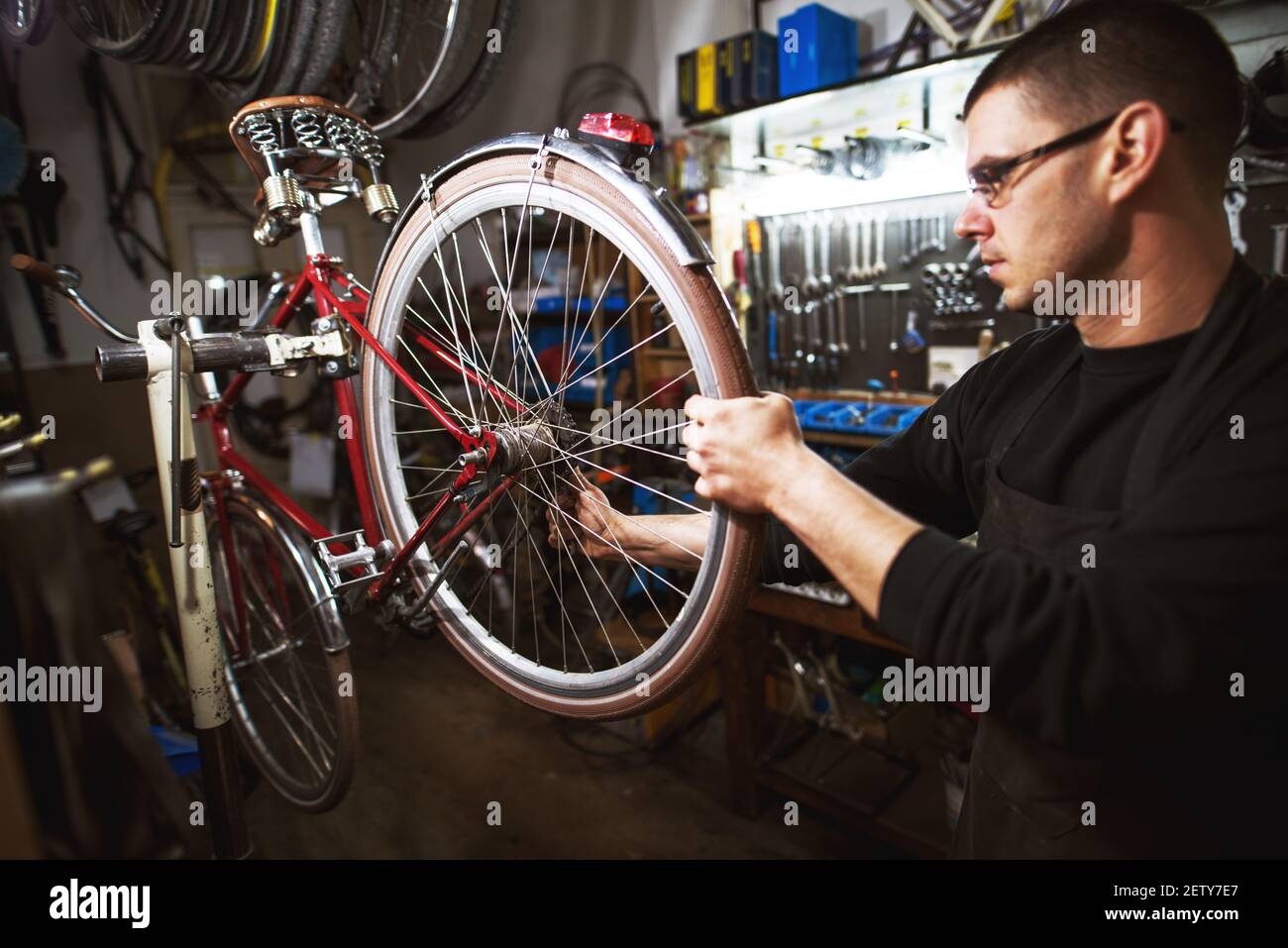 Professional young man checking bicycle wheel and wires Stock Photo - Alamy