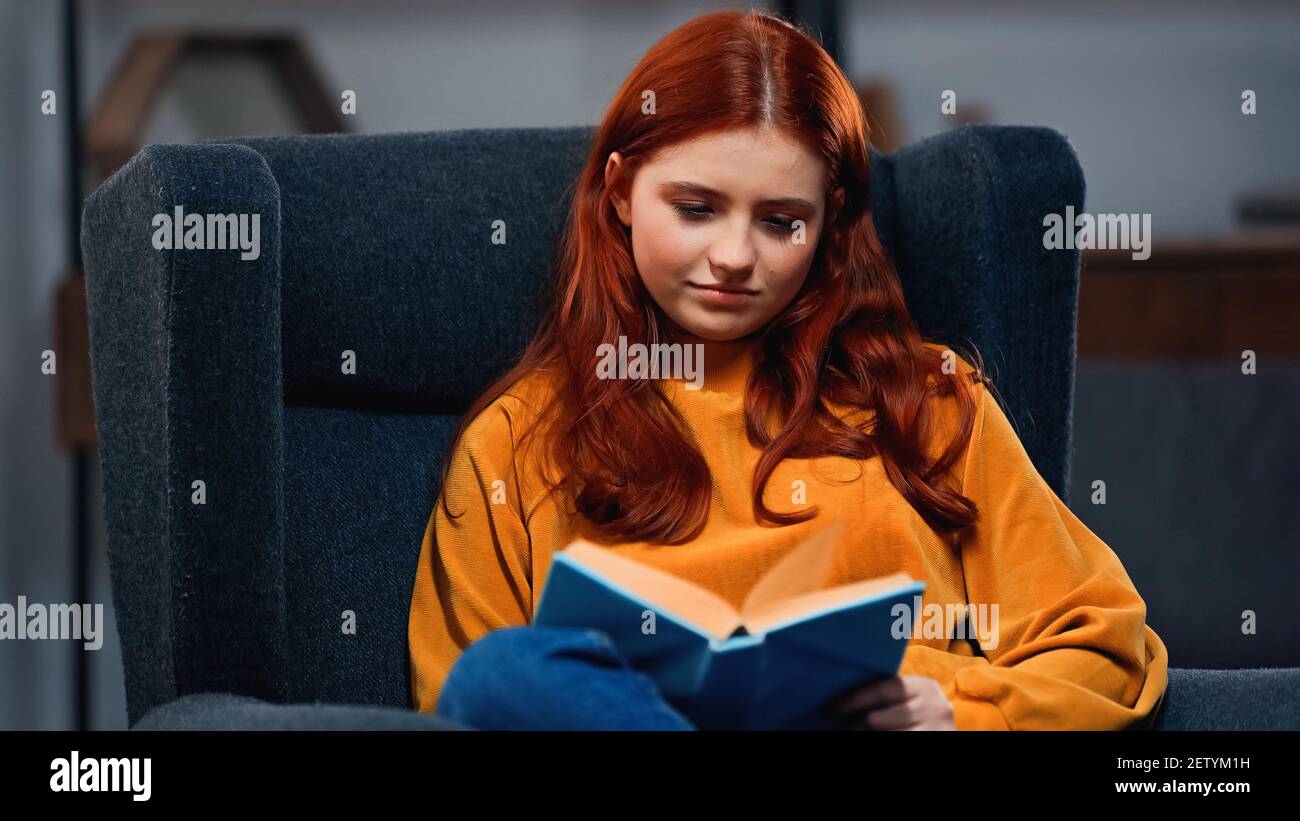 Teenager reading book on blurred foreground in armchair Stock Photo - Alamy