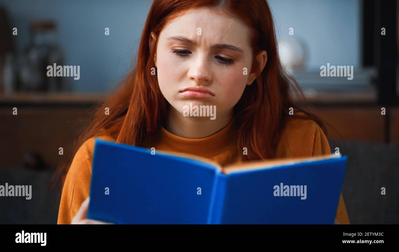 Sad girl reading book on blurred foreground Stock Photo - Alamy