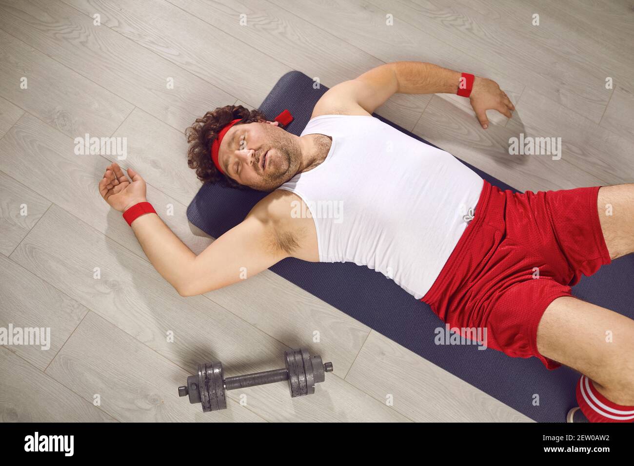 Tired chubby man lying on fitness mat after exhausting gym workout with ...