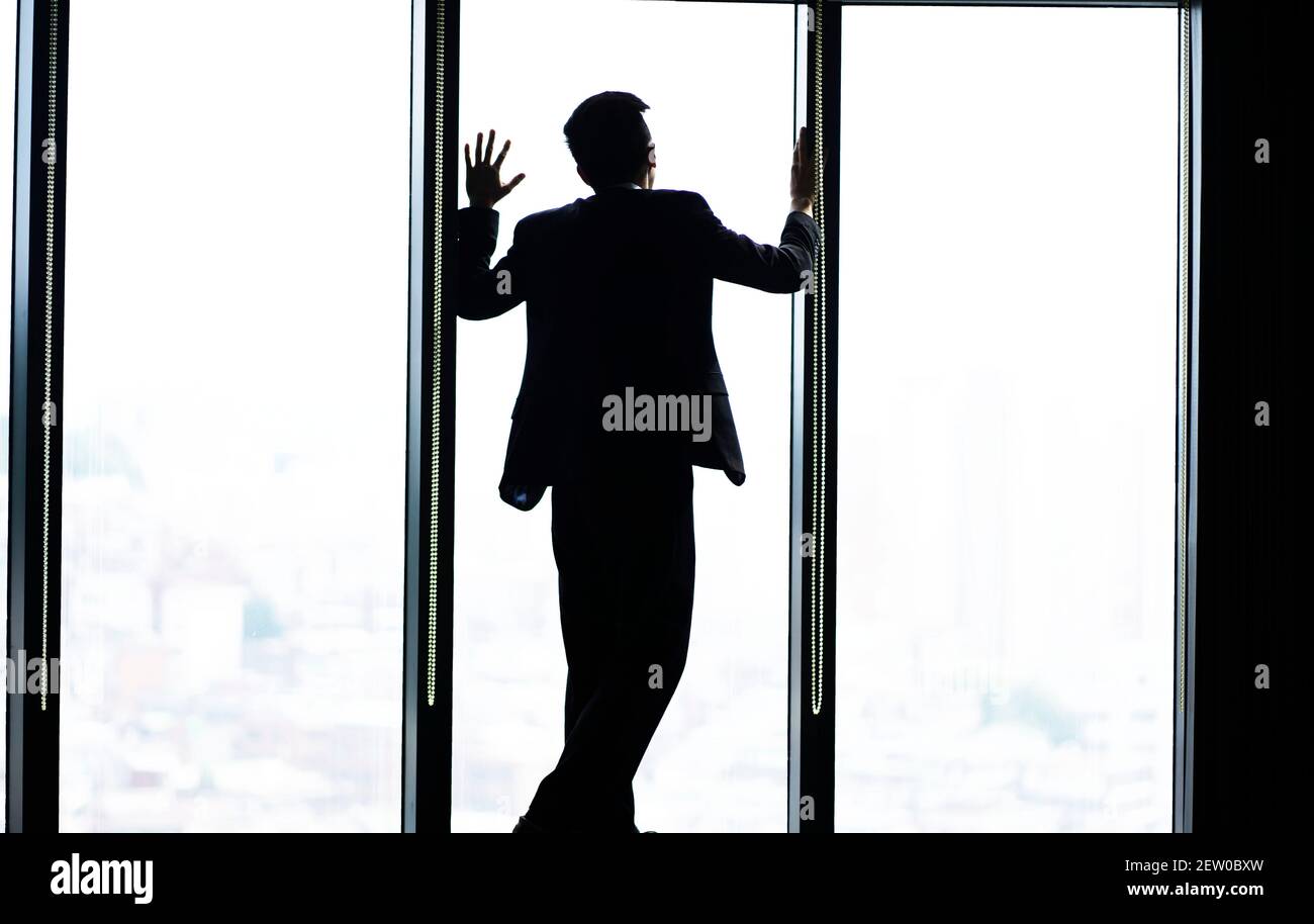 Pensive businessman looking through window Stock Photo - Alamy
