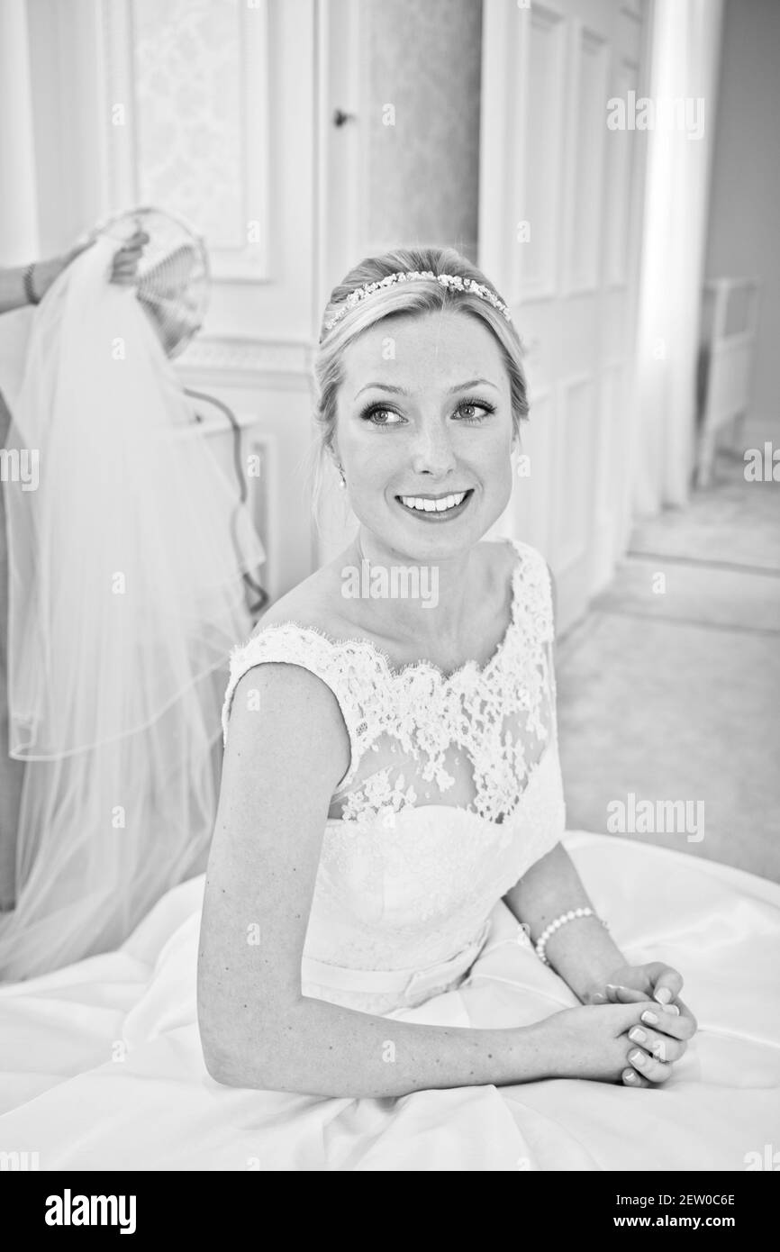 Bride seated wearing wedding dress looking very happy Stock Photo - Alamy