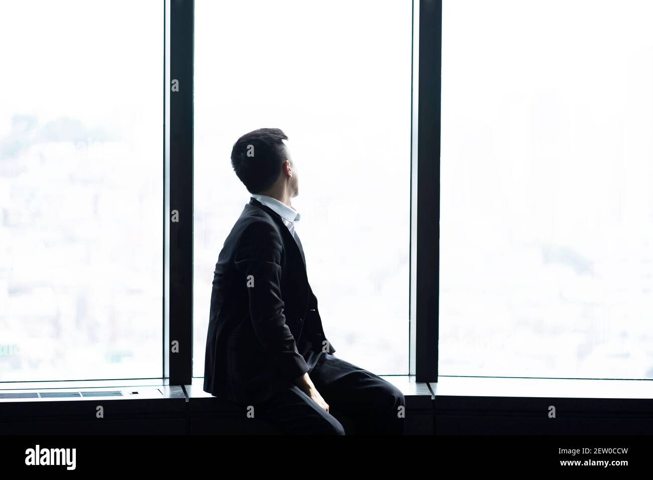 Businessman looking out of office window, looking pensive Stock Photo ...