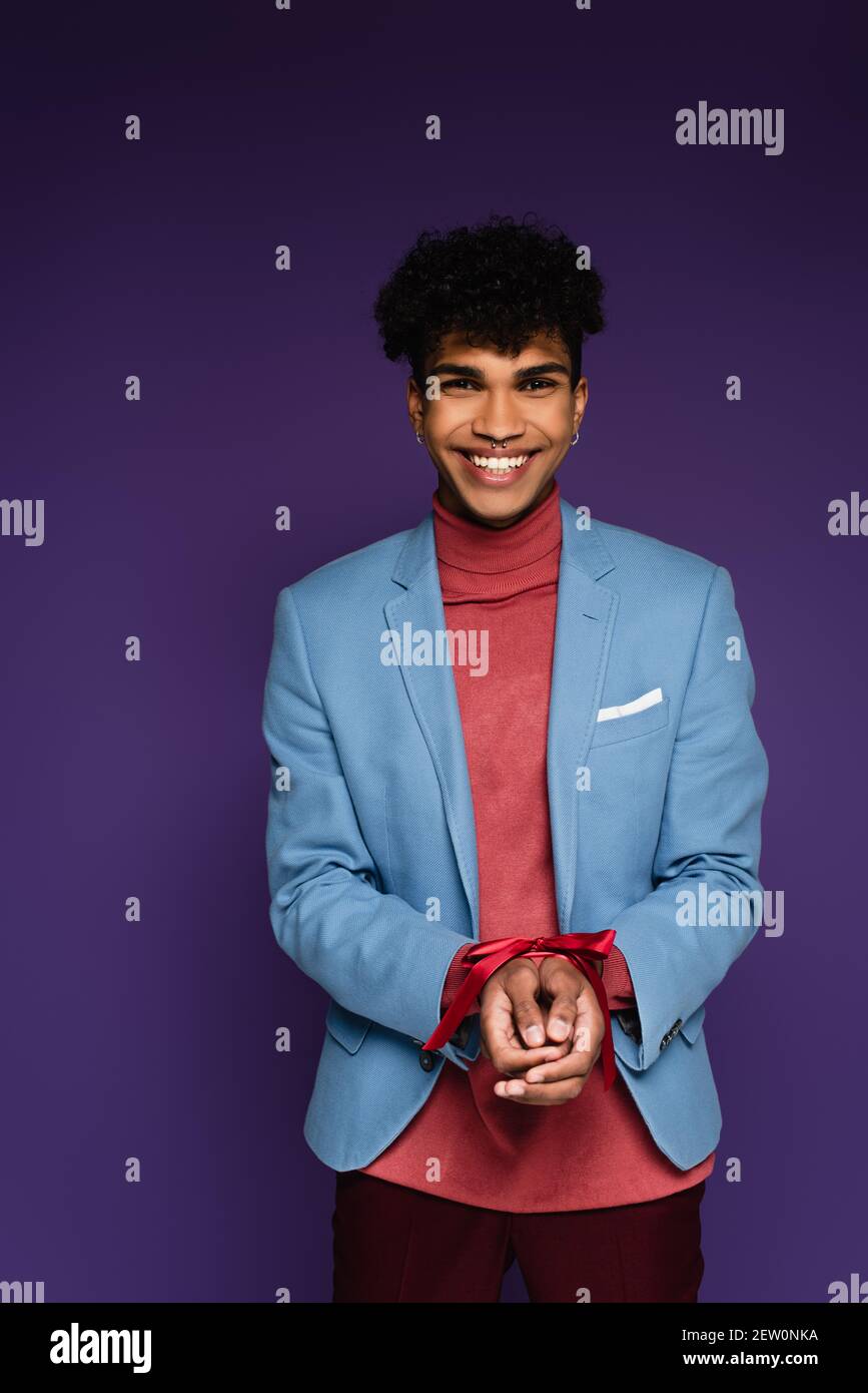 happy african american man tied with red ribbon on purple Stock Photo ...