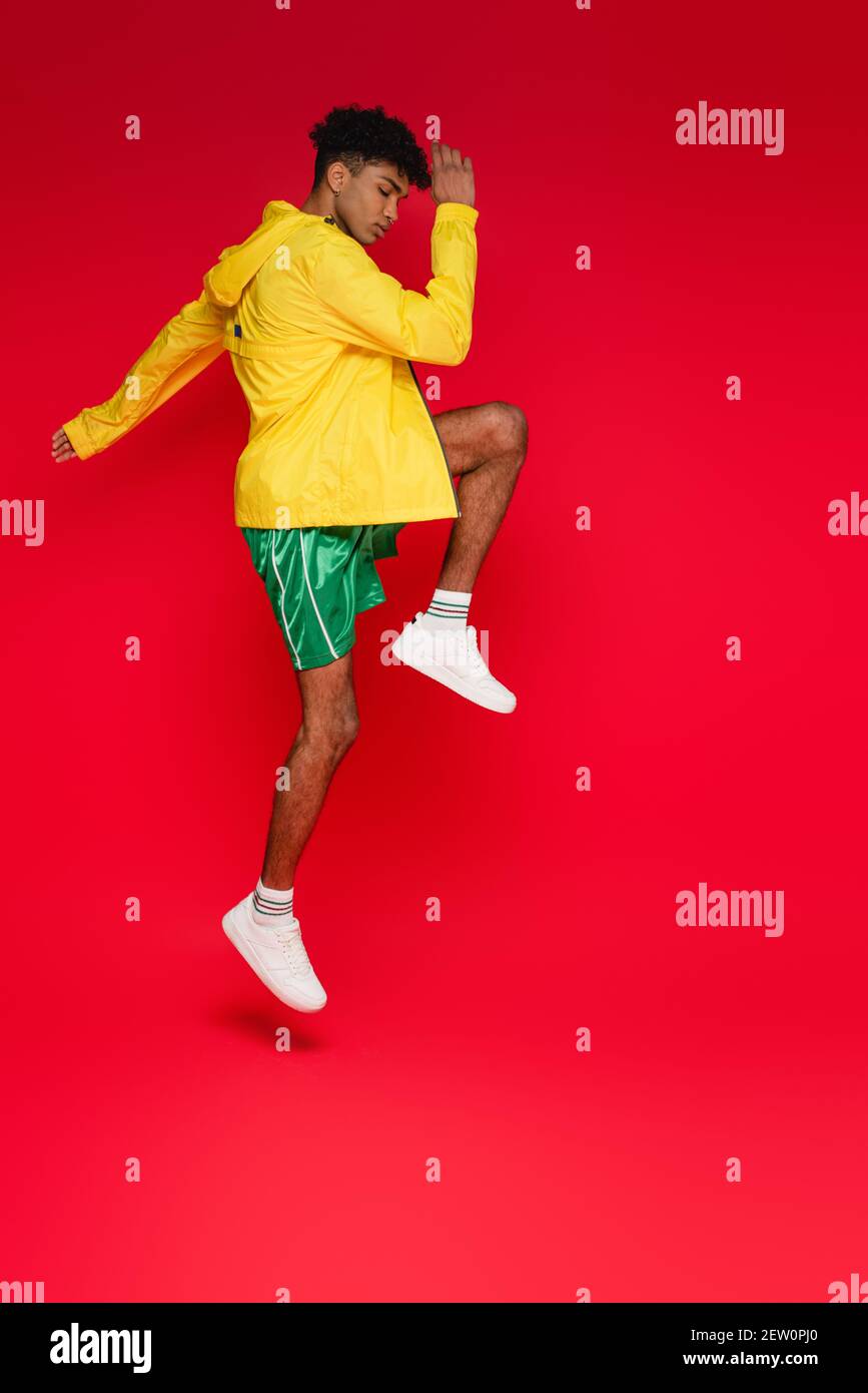 full length of sportive african american man in yellow jacket working ...