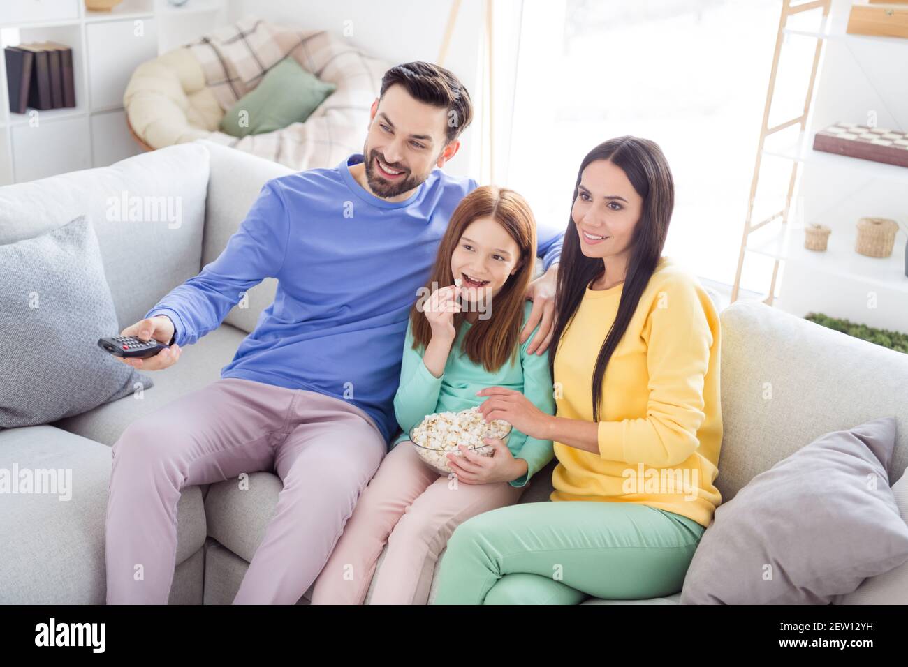 Photo of young family mom dad daughter happy positive smile eat popcorn ...