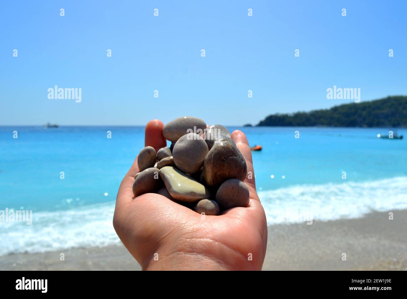 Hand holding rocks on the beach Stock Photo - Alamy