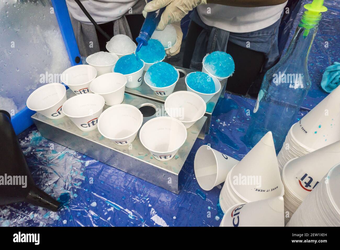 Workers prepare "Citicorp blue" snow cones to distribute as part of ...