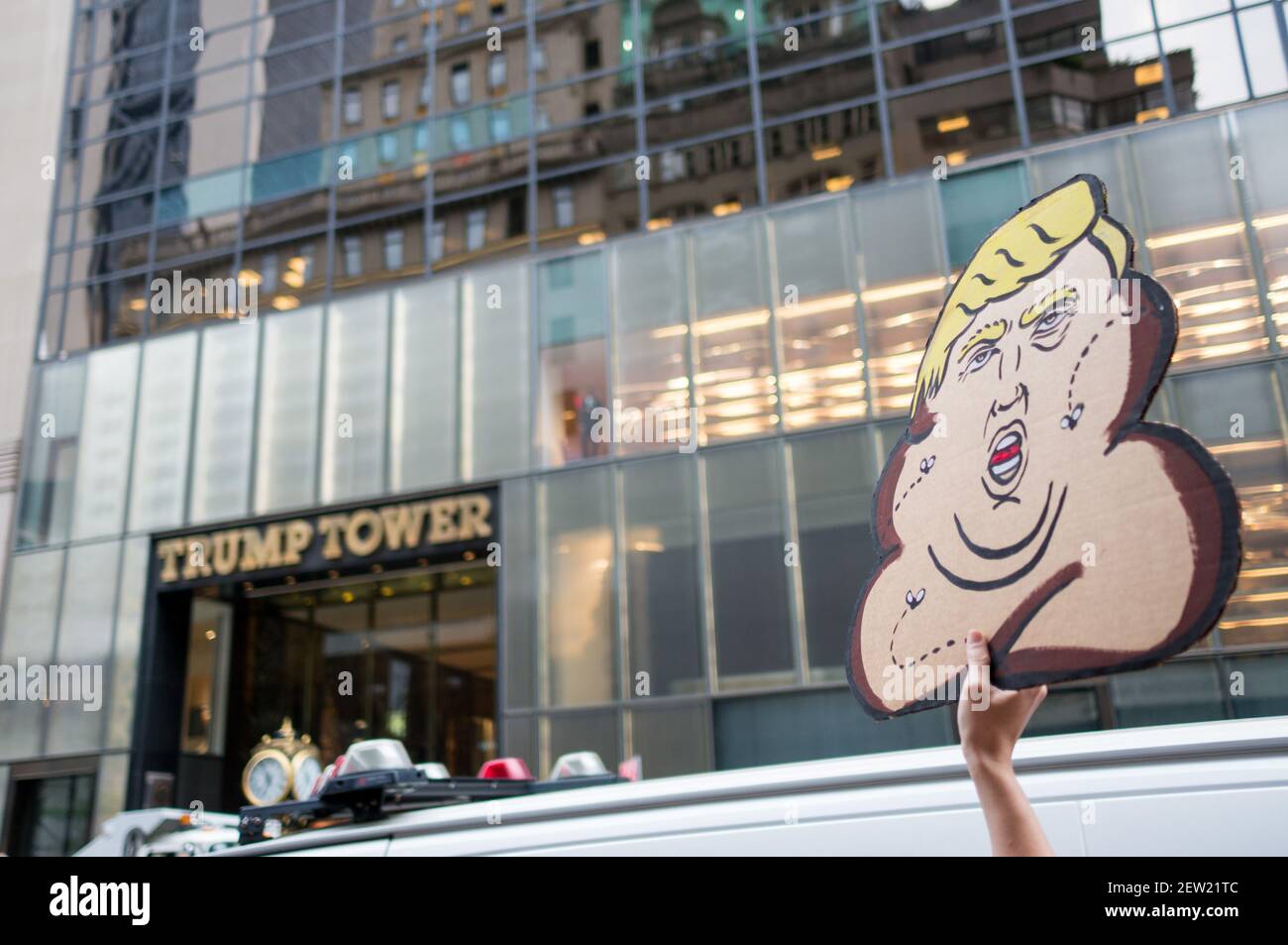 A protester holds up a sign that shows the president as a pile of feces ...