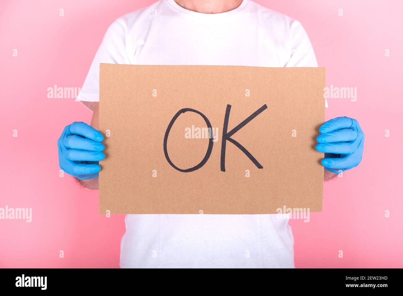 cardboard with OK message. Anonymous hands protected by gloves hold the ...
