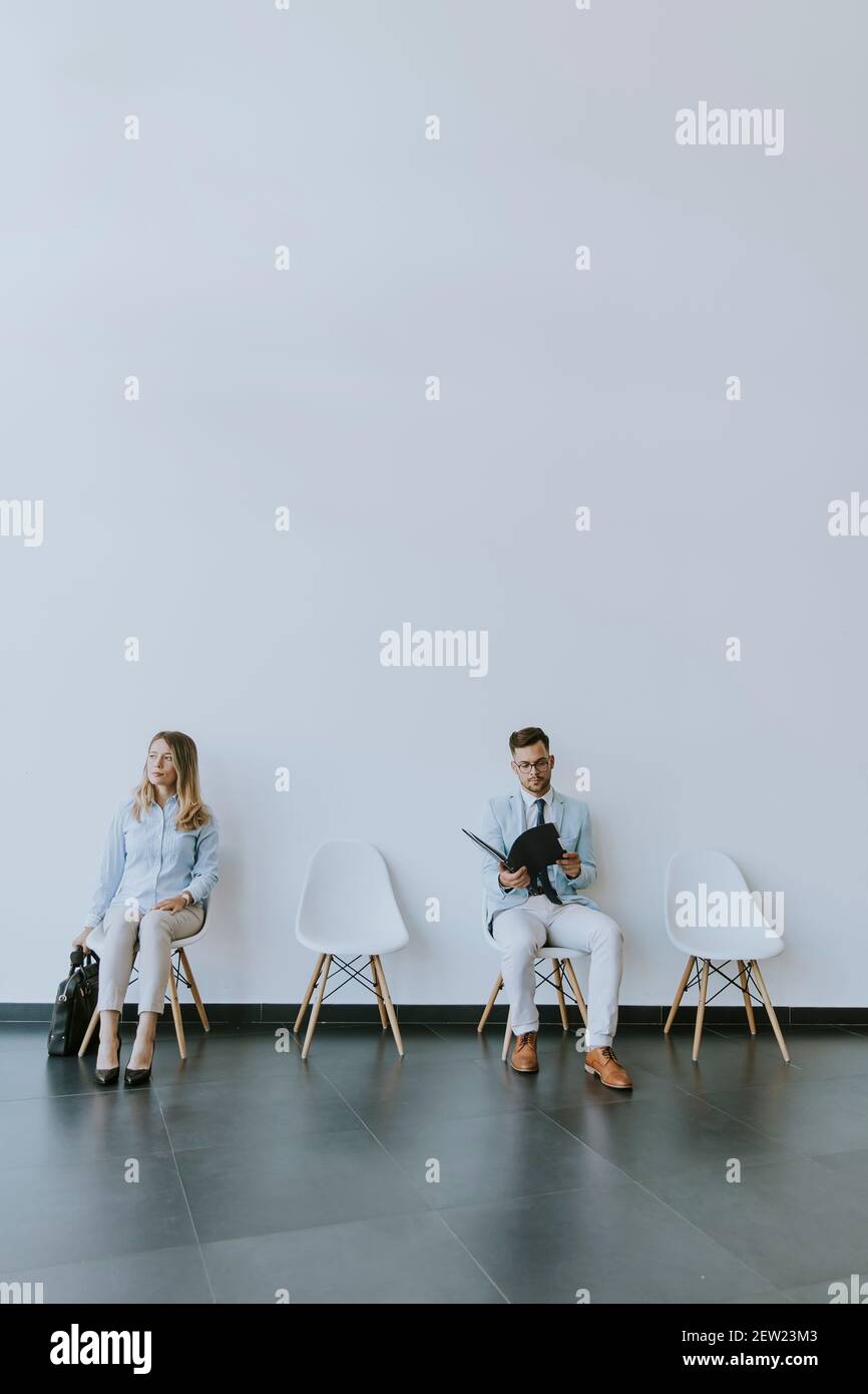 Young people sitting at chairs in the waiting room before an interview ...