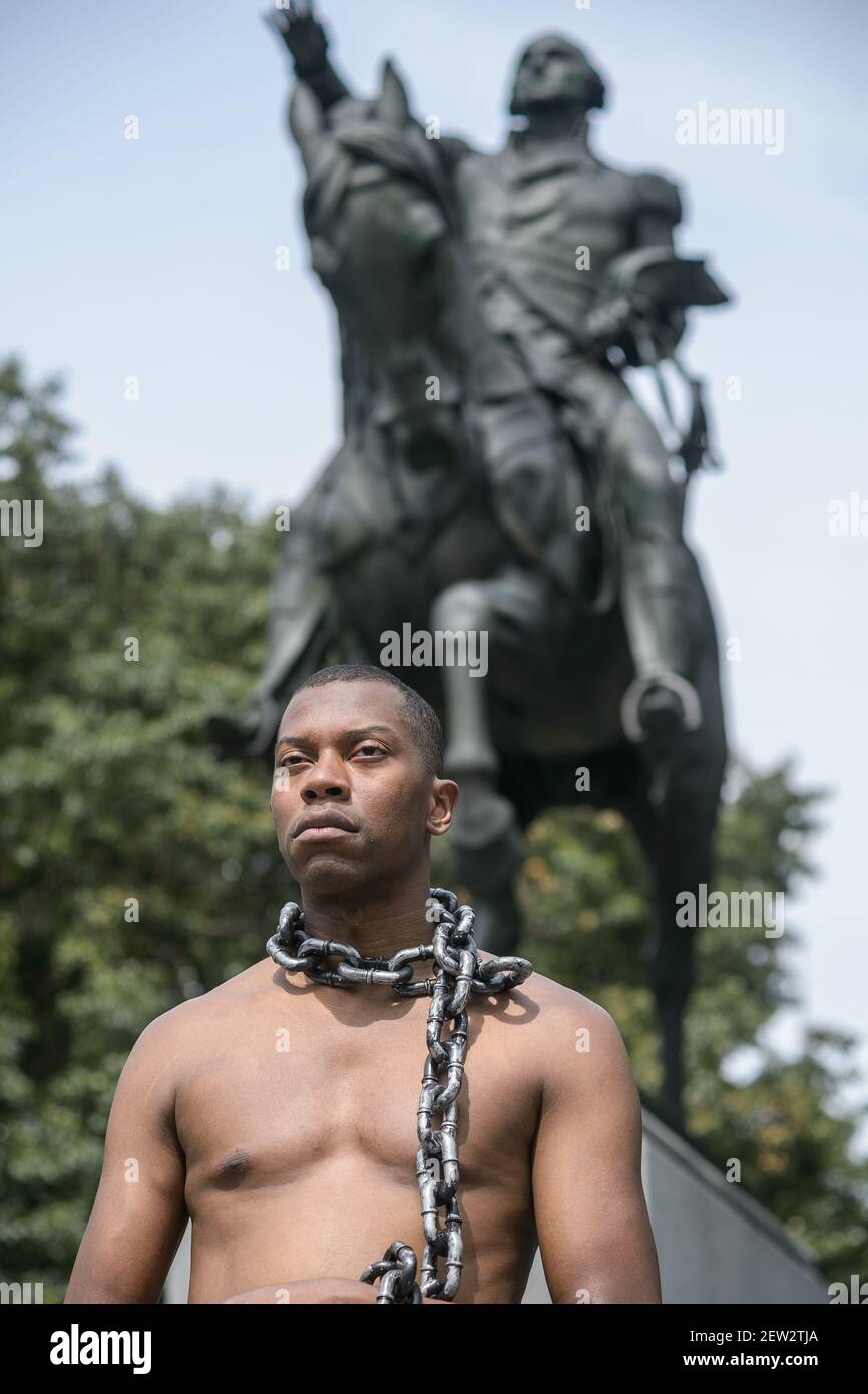 Three performance artists wearing chains standing atop wooden crates ...