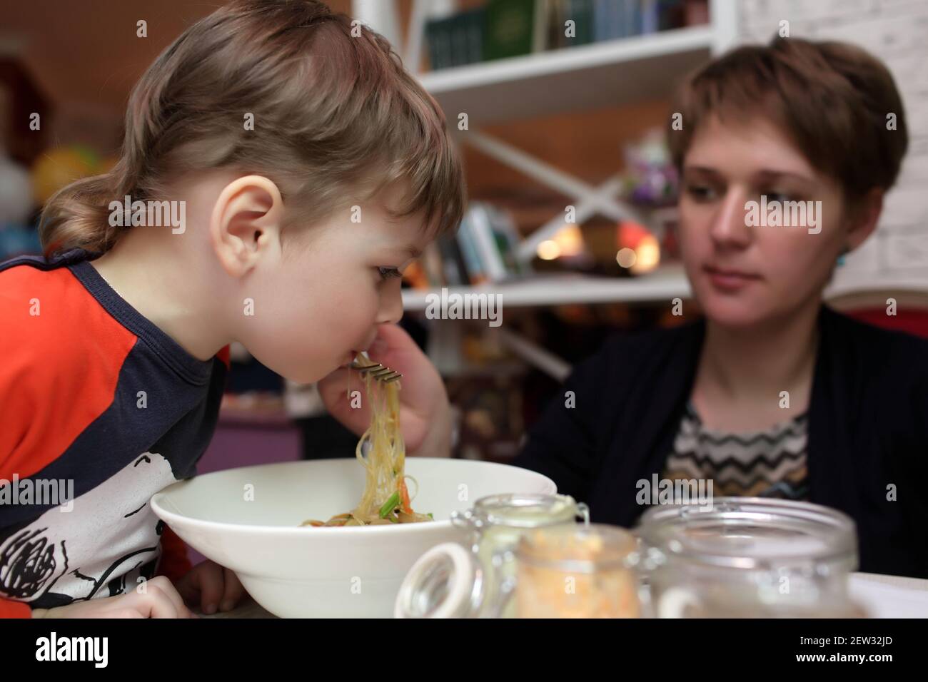 Mother feeds her son noodles in the restaurant Stock Photo - Alamy
