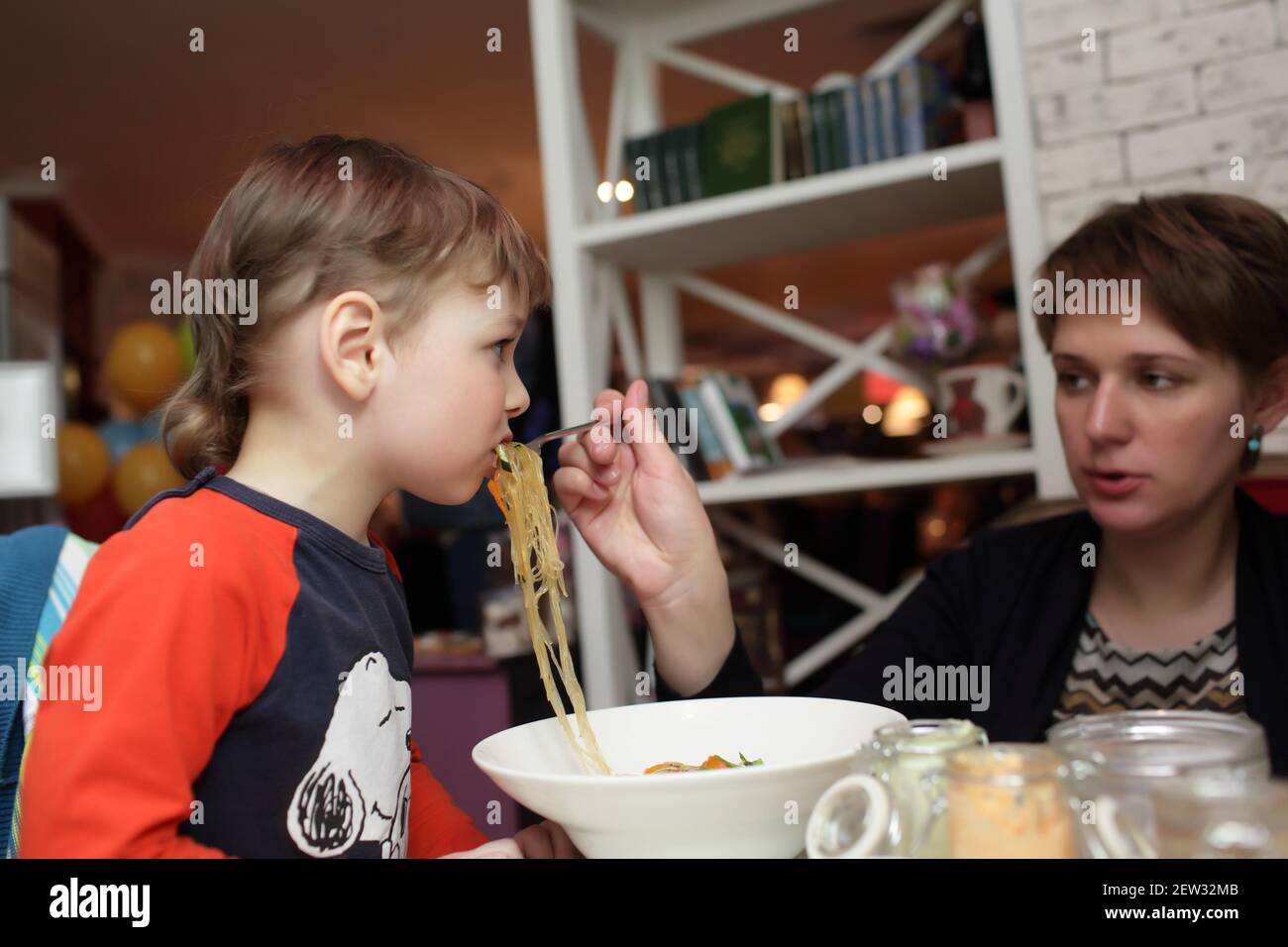 Mother with her son have noodles in the restaurant Stock Photo - Alamy