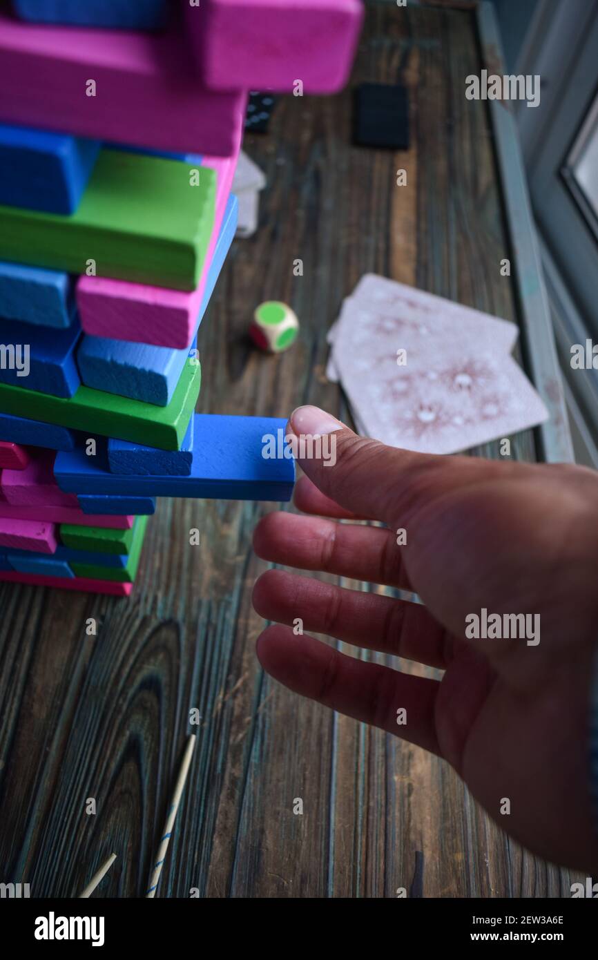 Top view of a hand pulling out a blue brick of Jenga game - table games ...