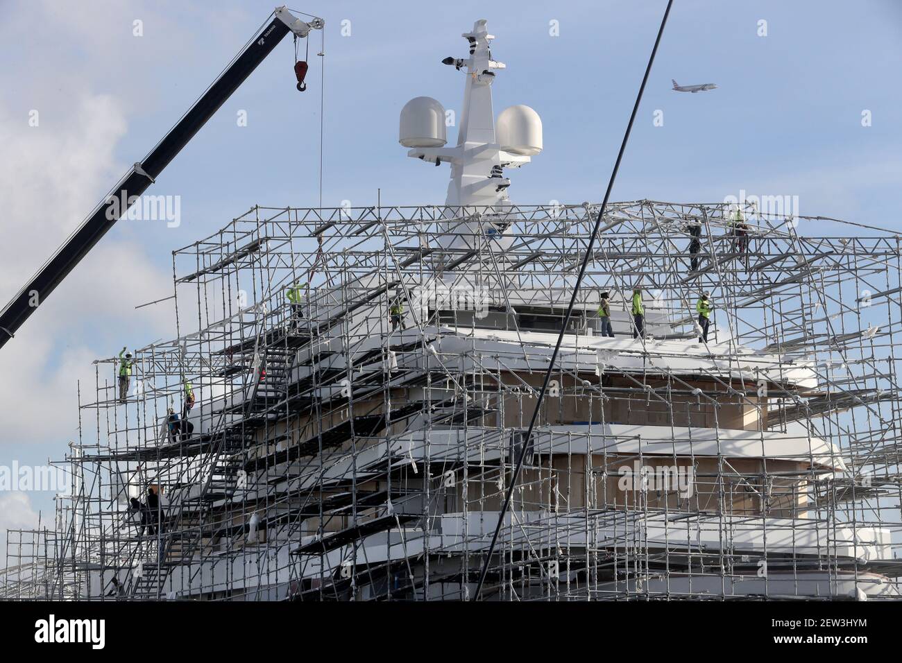 Construction workers dismantle scaffolding that encompasses a yacht ...