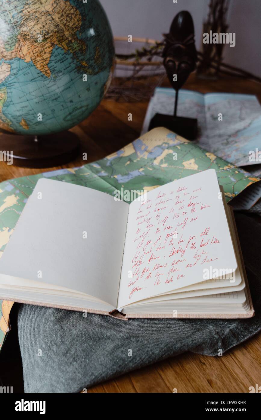 A vertical shot of maps, a globe and a diary with notes - travel and ...