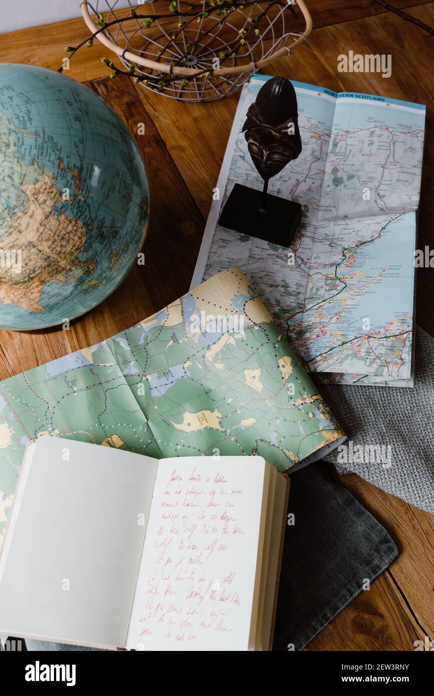 A vertical shot of maps, a globe and a diary with notes - travel and ...