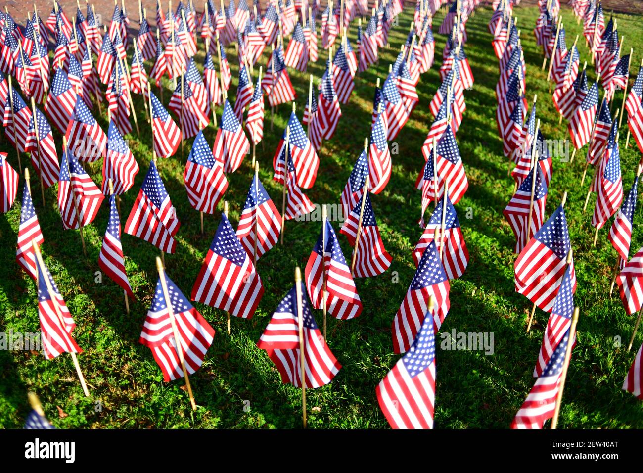 Many miniature US flags set on the grass in front of a memorial chapel ...
