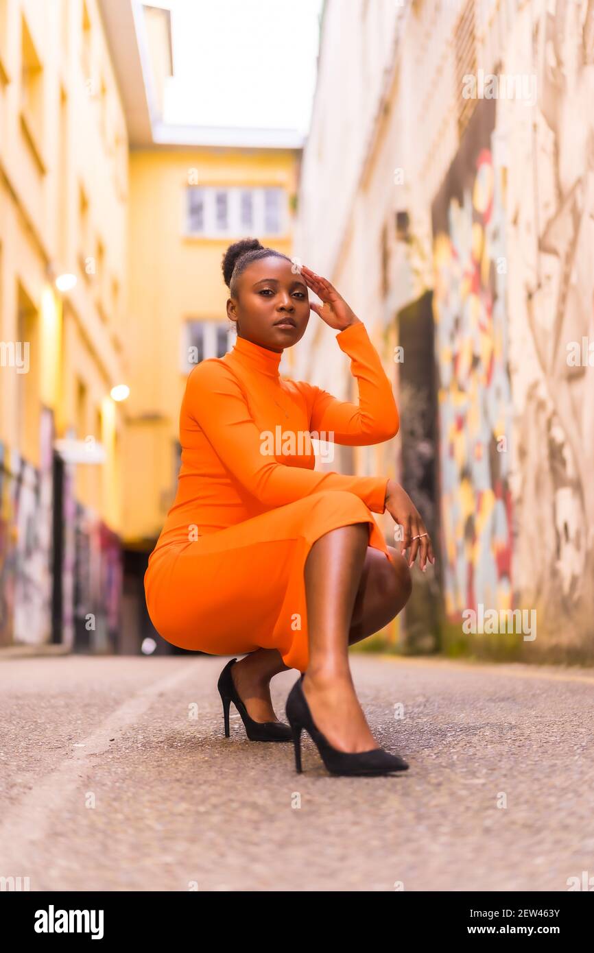 An African-American female model in an elegant orange dress posing ...