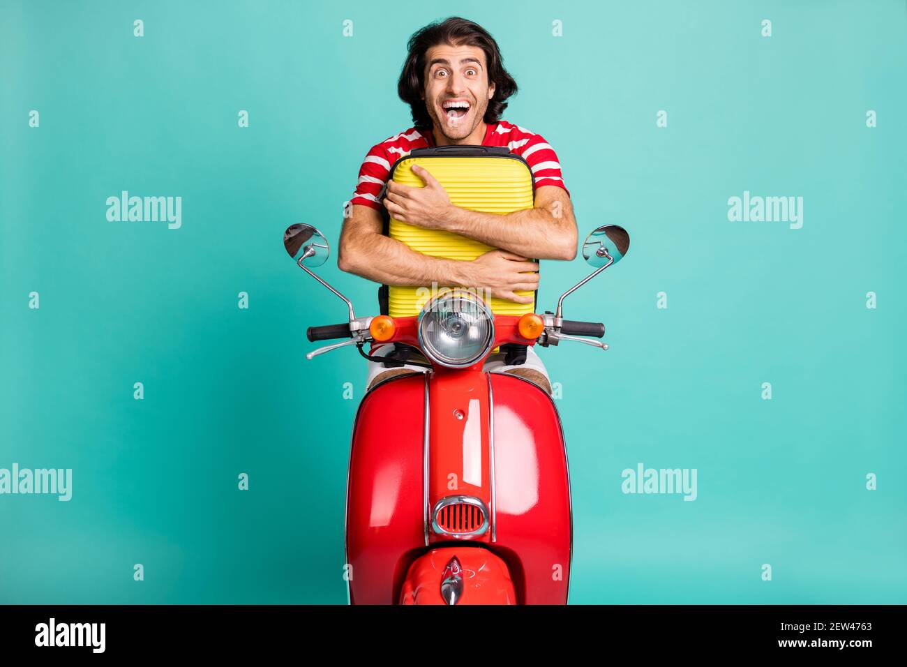 Portrait of handsome cheerful guy riding moped embracing bag isolated ...
