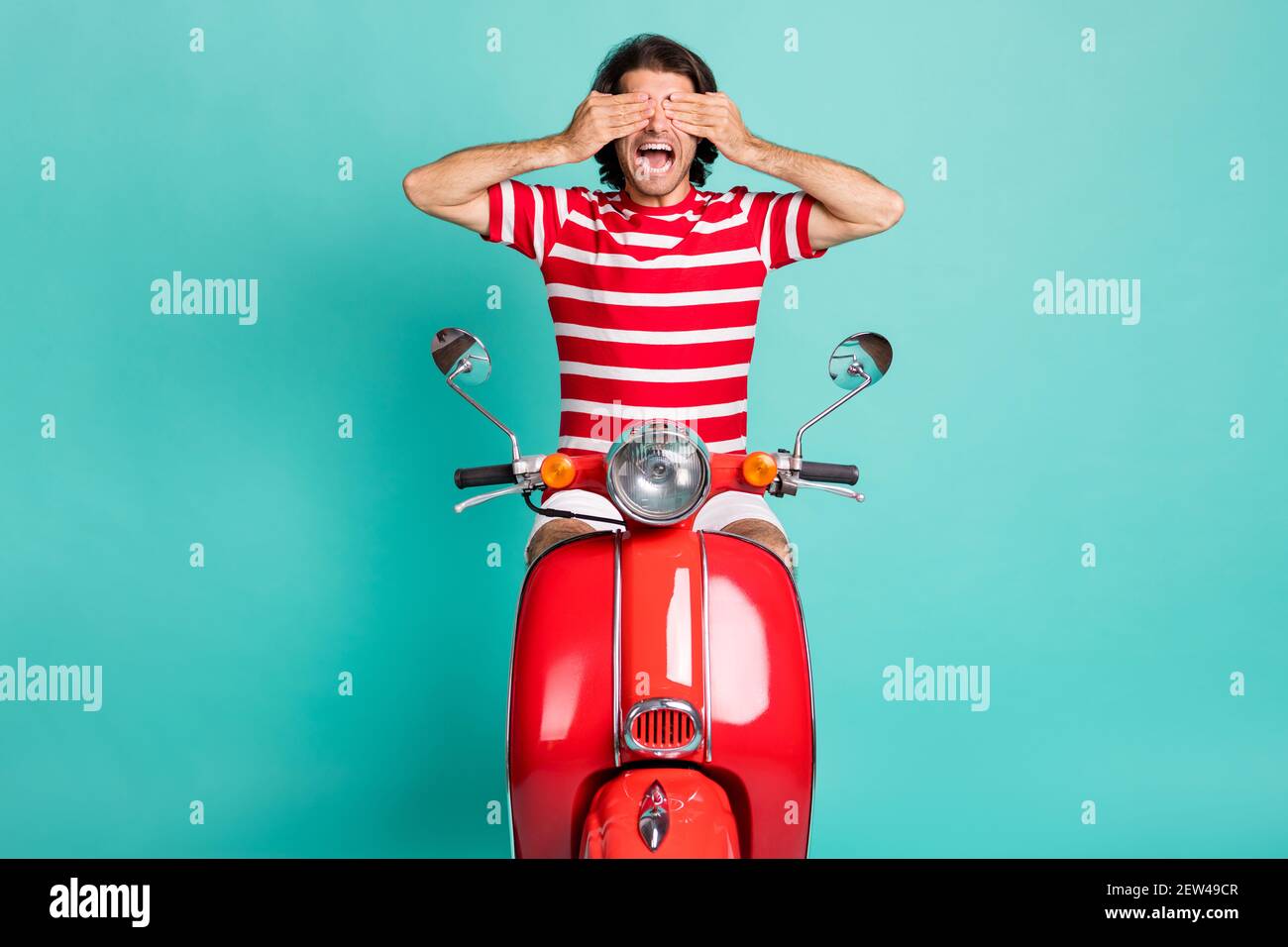 Portrait of nice cheerful funky guy riding moped having fun closing ...