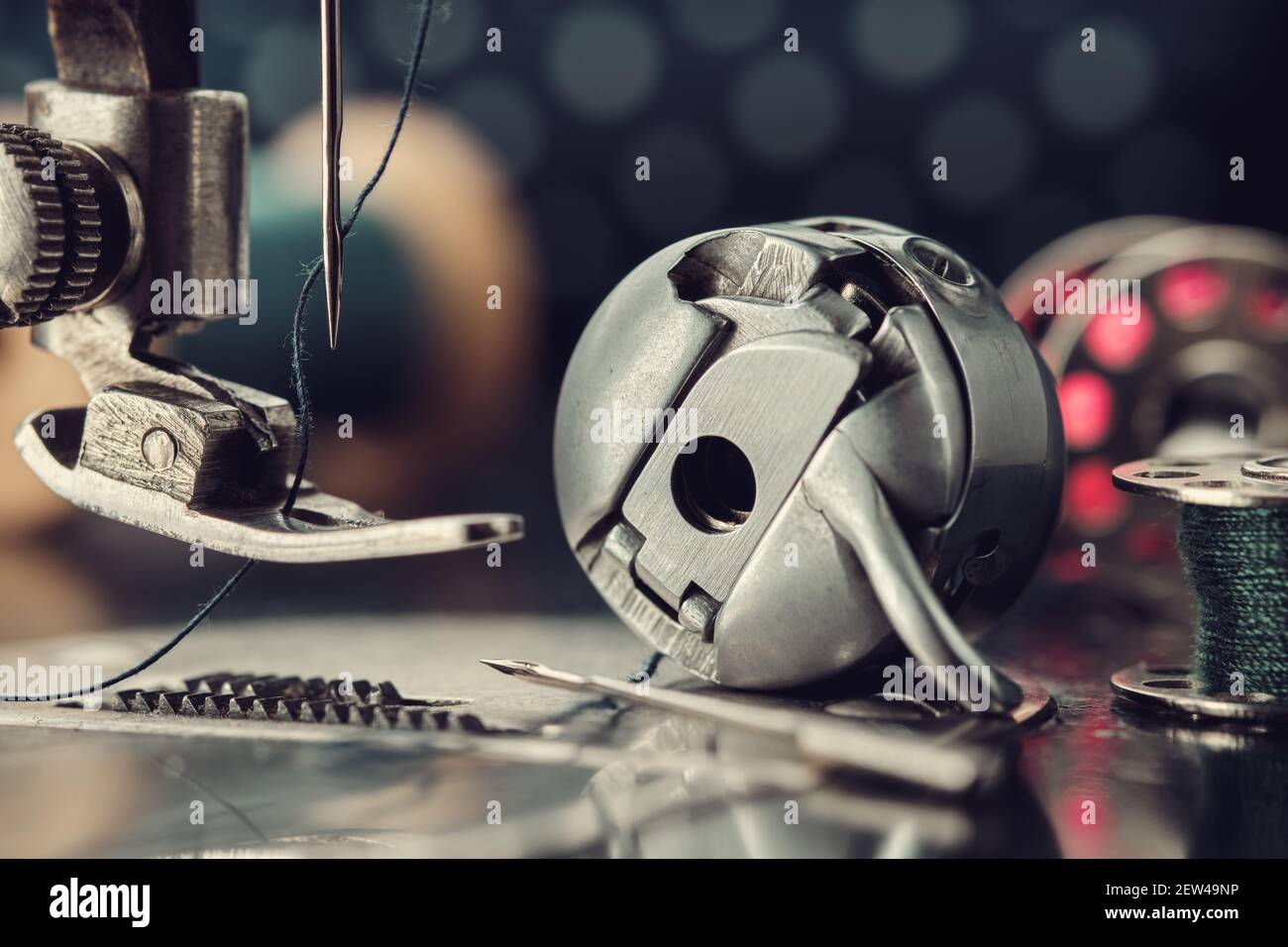 Close up on foot of vintage sewing machine, metal shuttle and spool of ...