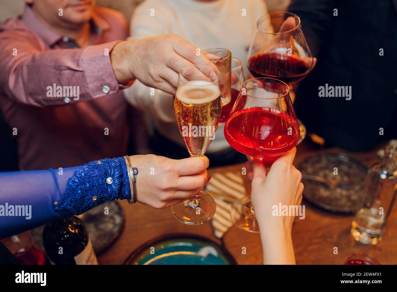 Clinking glasses with alcohol and toasting, party Stock Photo - Alamy
