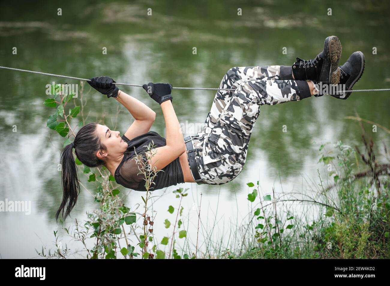 Female soldier conducts the rope bridge water crossing exercise. Water ...