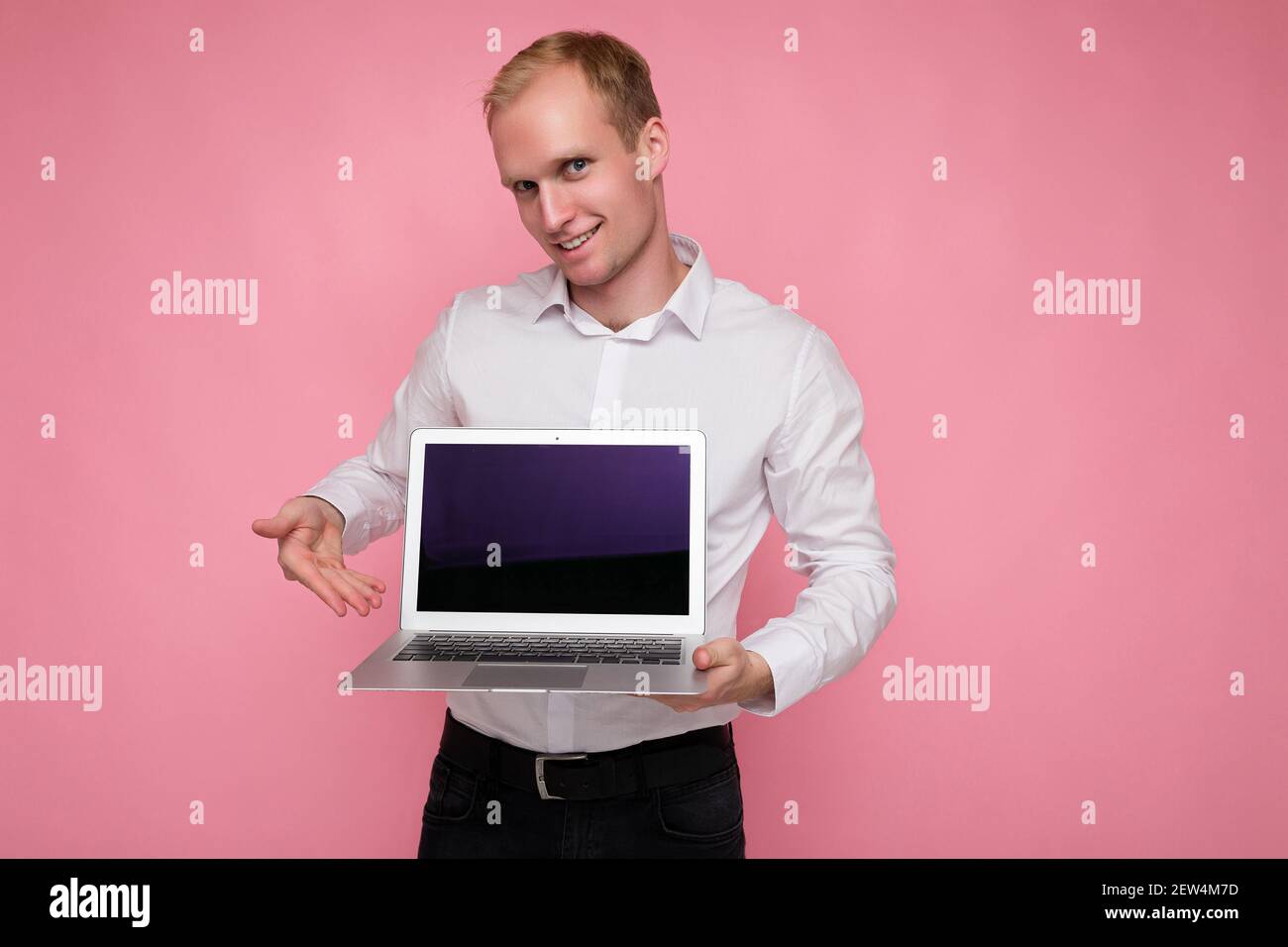 Photo shot of handsome smiling blonde man holding computer laptop with ...