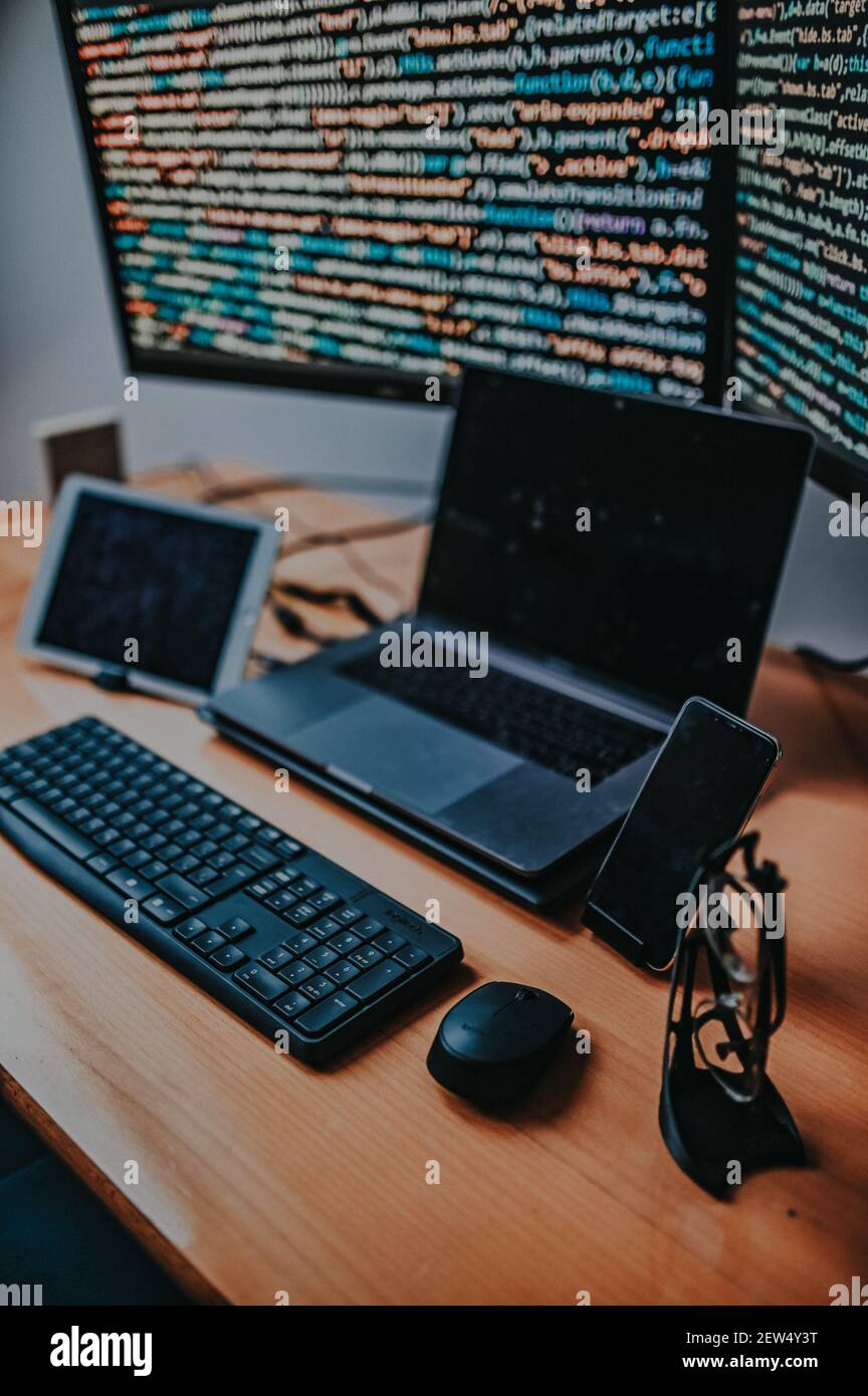 A vertical shot of programmer's desk with types of electronic equipment displaying codes Stock ...