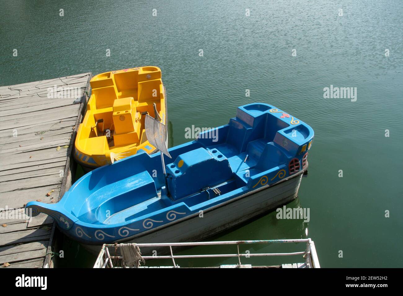 A weathered wooden dock with two yellow and blue pedal boats Stock ...
